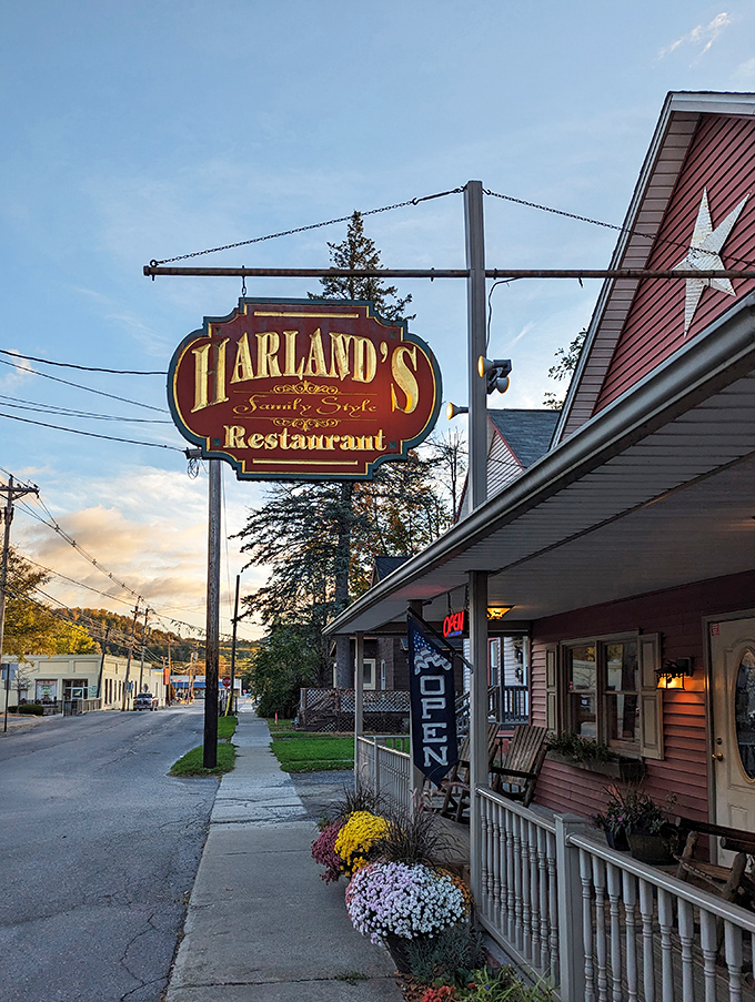 Harland's Restaurant's vintage sign swings above a flower-adorned entrance, promising "Family Style" meals that grandmother would approve of—comfort food headquarters.