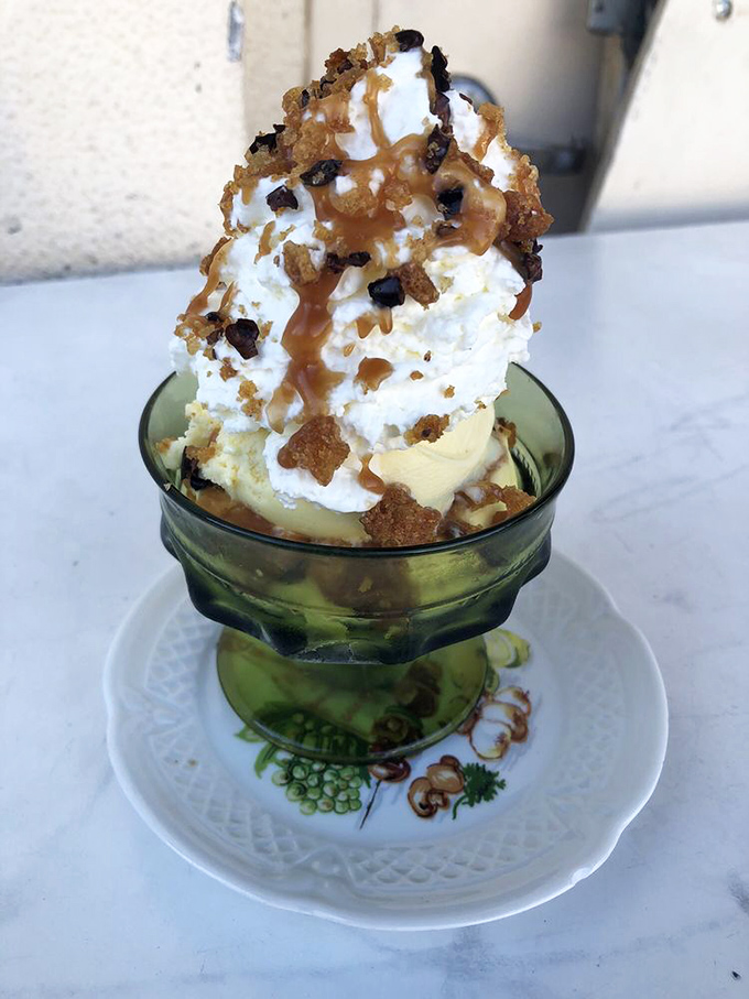 This sundae isn't just dessert; it's performance art in a vintage glass, topped with caramel and cookie crumbles like a sweet jazz improvisation.