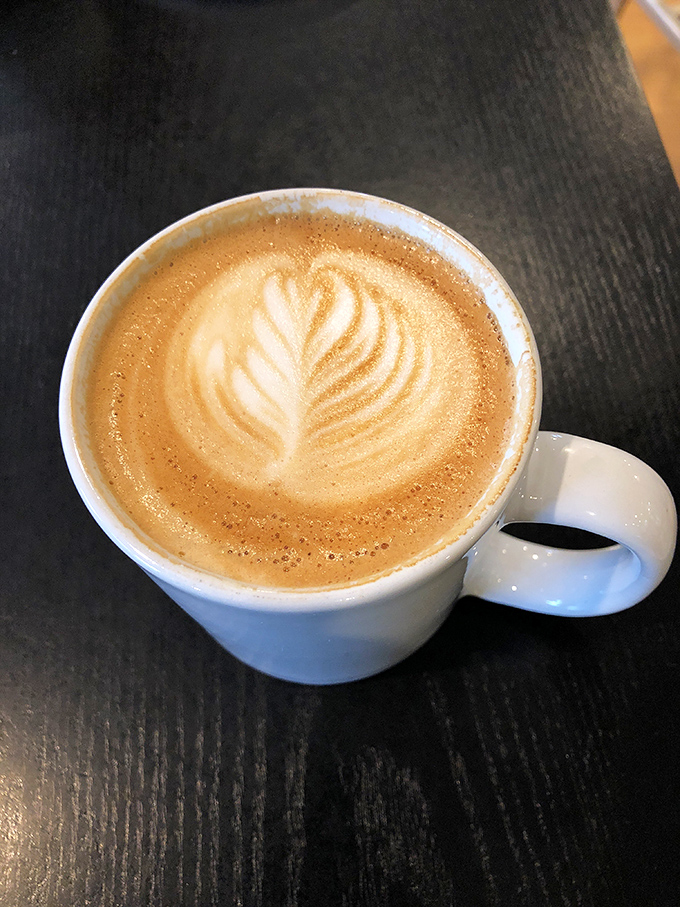 This latte isn't just coffee; it's liquid architecture with foam sculpted into a leaf pattern that deserves its own tiny art gallery.