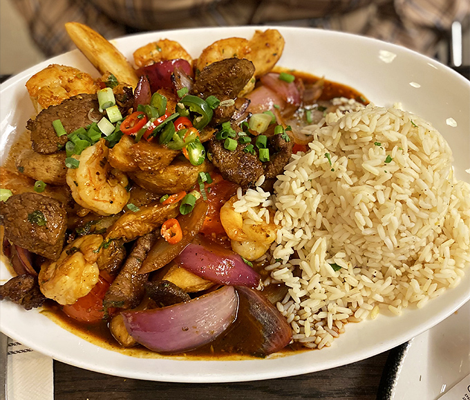 A plate that crosses continents: tender beef, plump shrimp, and colorful vegetables dance in savory sauce alongside perfectly cooked rice. Geography never tasted so good.