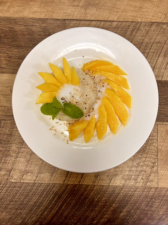 Mango sticky rice that looks like sunshine decided to become dessert. The coconut milk pooling around those golden slices is nature's perfect sauce.