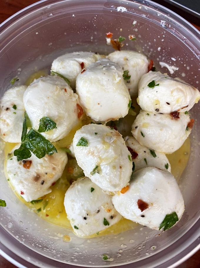 Fresh mozzarella balls bathing in herbed olive oil&mdash;little orbs of dairy perfection that might not make it home before being devoured.