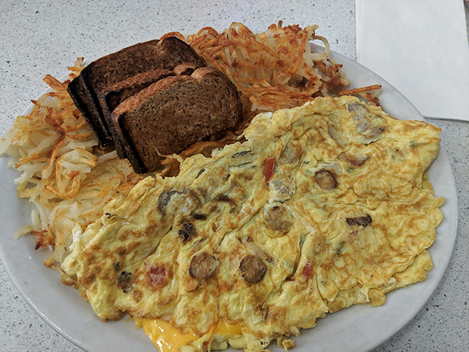 An omelet that clearly graduated with honors from the School of Hearty Breakfasts, accompanied by hash browns and toast for moral support.