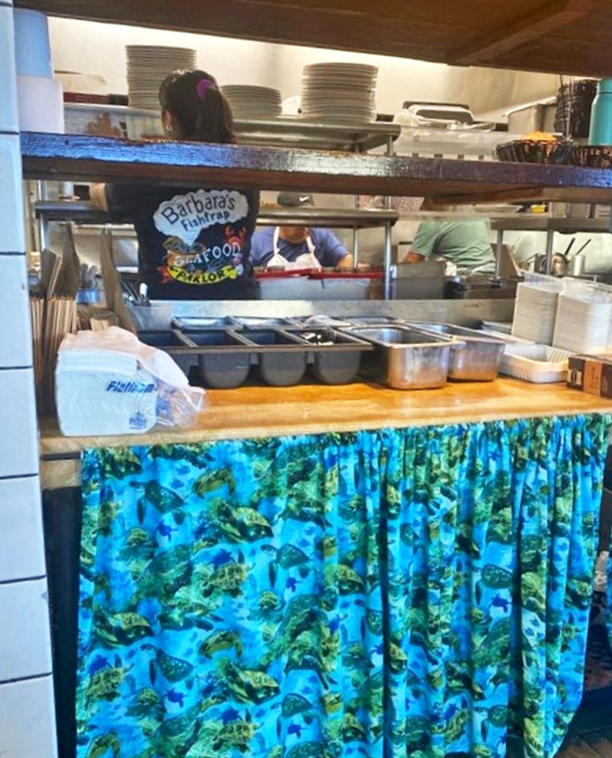 Behind the scenes where the magic happens&mdash;staff in the open kitchen preparing ocean treasures. That blue fish-patterned curtain is the culinary equivalent of a superhero's cape.