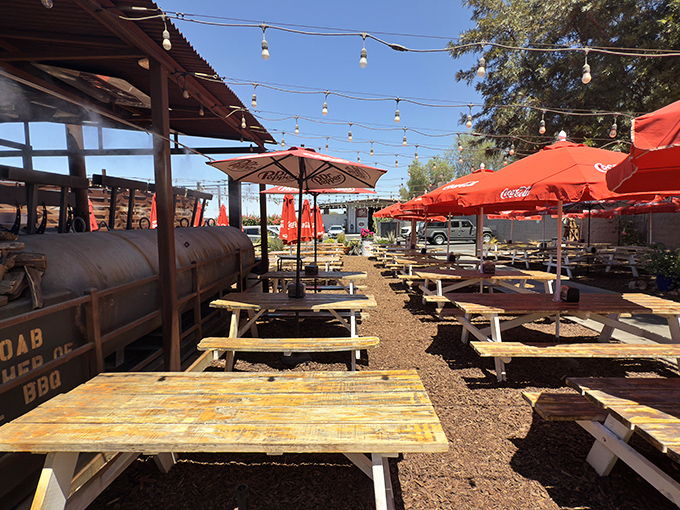 The outdoor seating area, where string lights and Coca-Cola umbrellas create the perfect Arizona setting for enjoying Texas-style BBQ under desert skies.