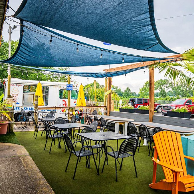The outdoor patio offers a breath of fresh air under blue canopies, where summer meals taste even better.