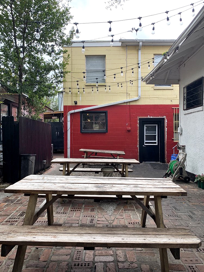 The backyard picnic area: where string lights twinkle above wooden tables, and the brick patio has absorbed years of happy barbecue conversations.