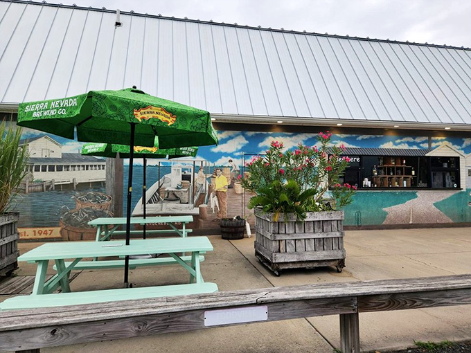 The outdoor patio features turquoise picnic tables and a mural depicting the Chesapeake Bay, creating a perfect spot for summer crab feasts.