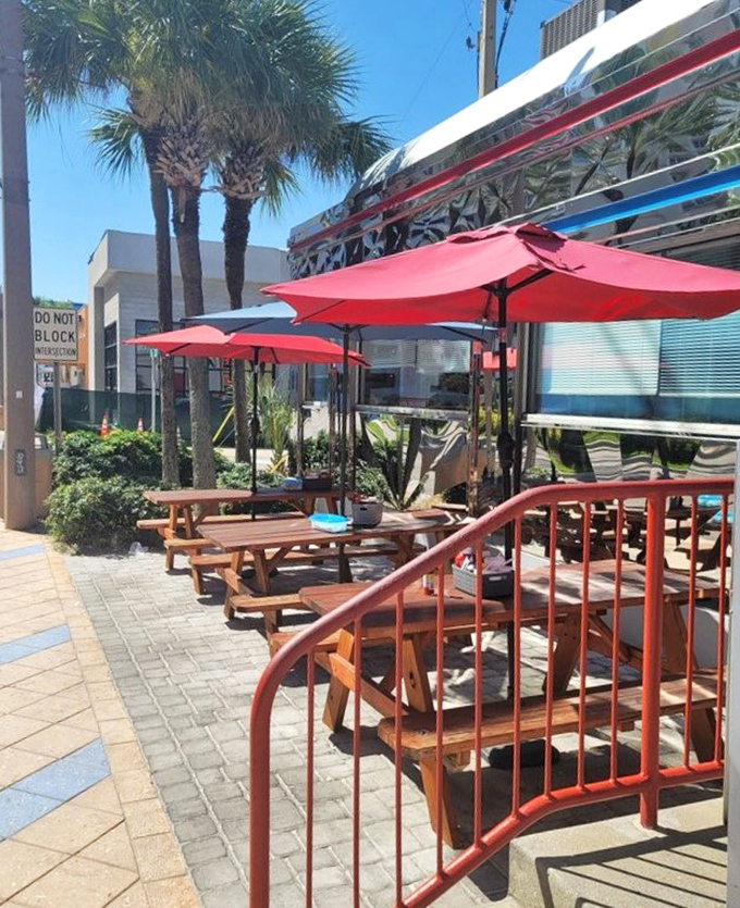Florida sunshine and palm trees create the perfect backdrop for Starlite's outdoor seating area, where wooden picnic tables invite alfresco dining under red umbrellas.