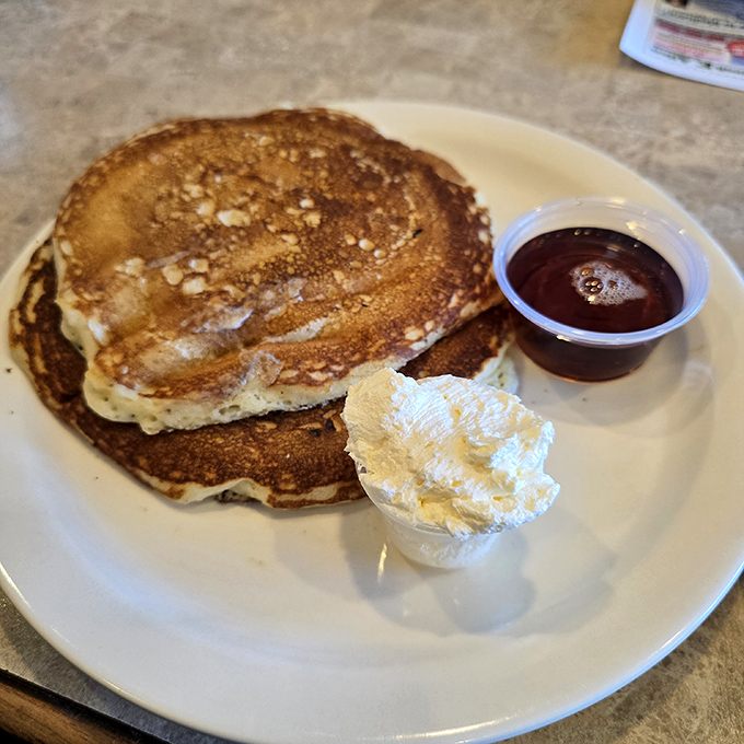 Golden pancakes with the perfect crispy edge, a dollop of butter melting into their fluffy centers. Maple syrup standing by for its grand entrance.