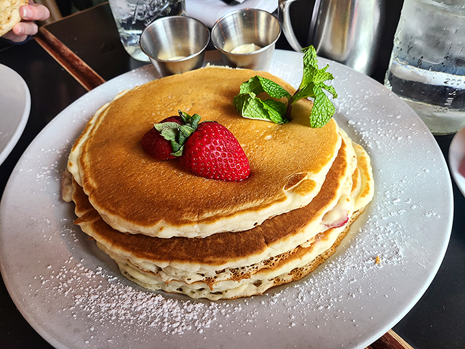 Pancakes stacked higher than your weekend to-do list, with a strawberry on top that's basically saying, "Take that, boring breakfast!" Powdered sugar snow adds the perfect finish.
