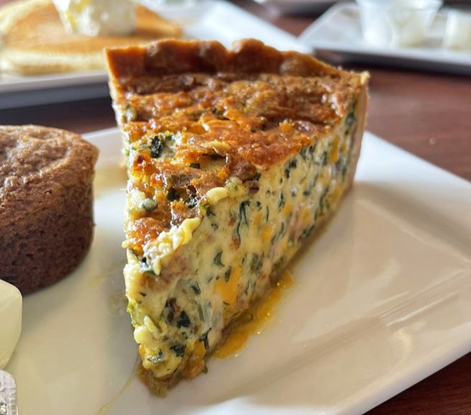 A quiche slice that stands tall and proud, revealing its secrets in cross-section. A savory pie that makes vegetables feel like they're attending a fancy party.