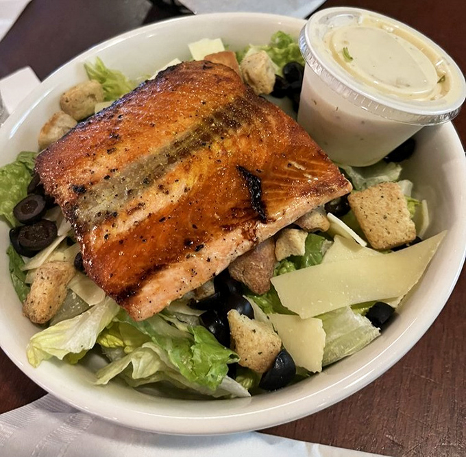 A perfectly grilled salmon filet crowns this Caesar salad, offering a protein-packed option that doesn't sacrifice flavor for healthfulness.
