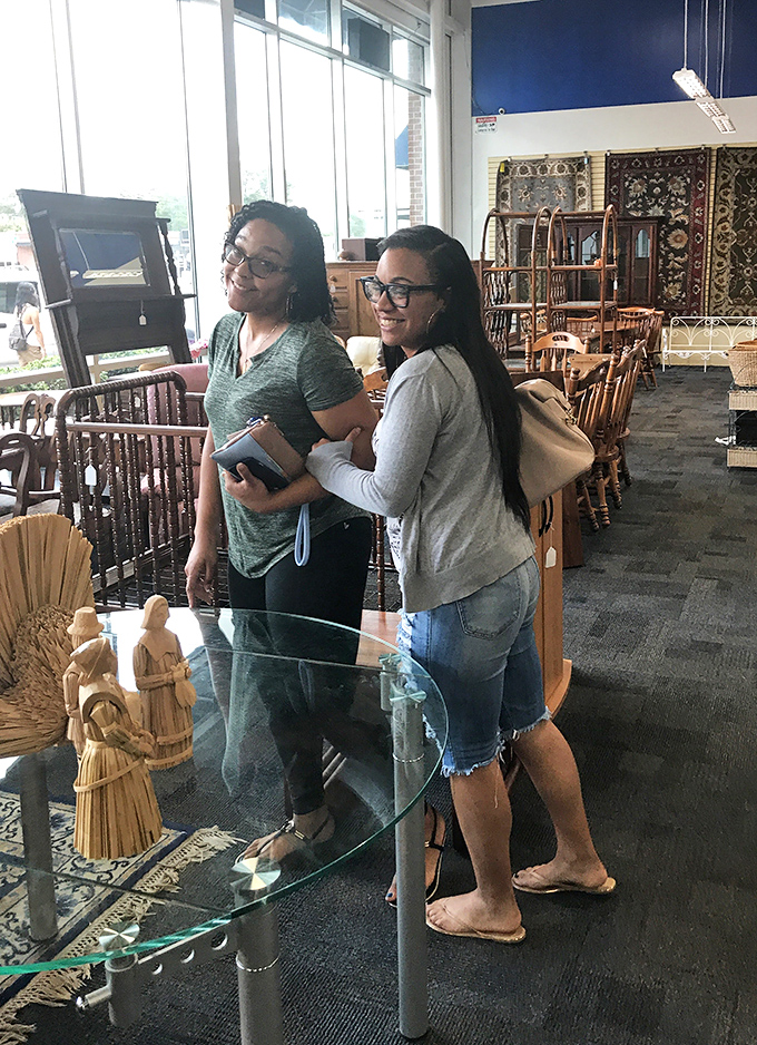 Happy shoppers exploring the furniture section, proving that thrifting is better with friends who appreciate the thrill of the hunt.