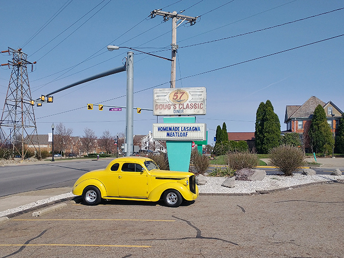The roadside sign beckons like a lighthouse for hungry travelers, with a classic car parked beneath as if time itself is taking a lunch break.