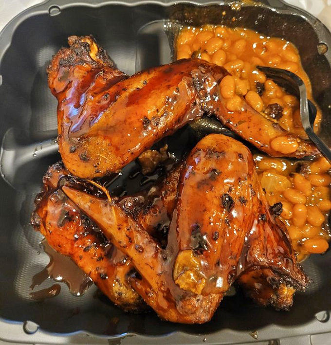 BBQ wings glistening with sauce alongside baked beans that have clearly been simmering their way to perfection. Napkins required, regrets impossible.