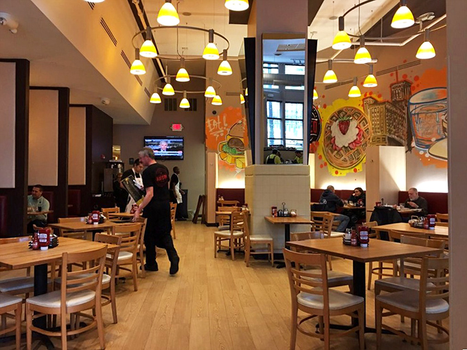 Yellow pendant lights illuminate the space where breakfast dreams come true, with whimsical food-themed artwork adding splashes of color to every wall.