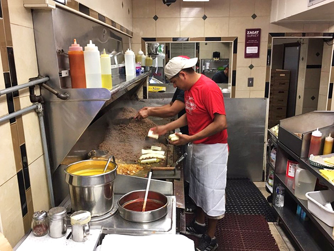 Behind the scenes magic: a skilled cook transforms simple ingredients into legendary sandwiches with practiced precision and care.