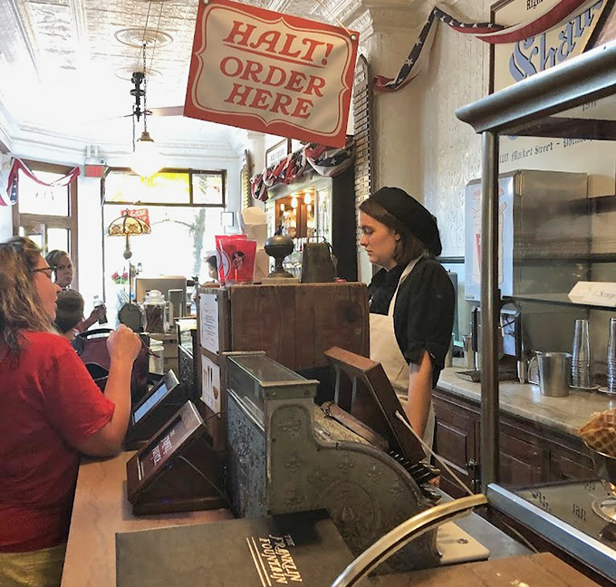 The sacred transaction: ordering at the counter. That "Halt!" sign isn't just cute—it's necessary crowd control for a place this beloved.