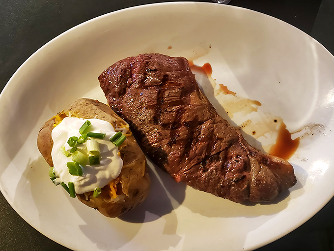 A steak that needs no introduction, perfectly seared and resting beside a loaded baked potato that's dressed for the occasion.