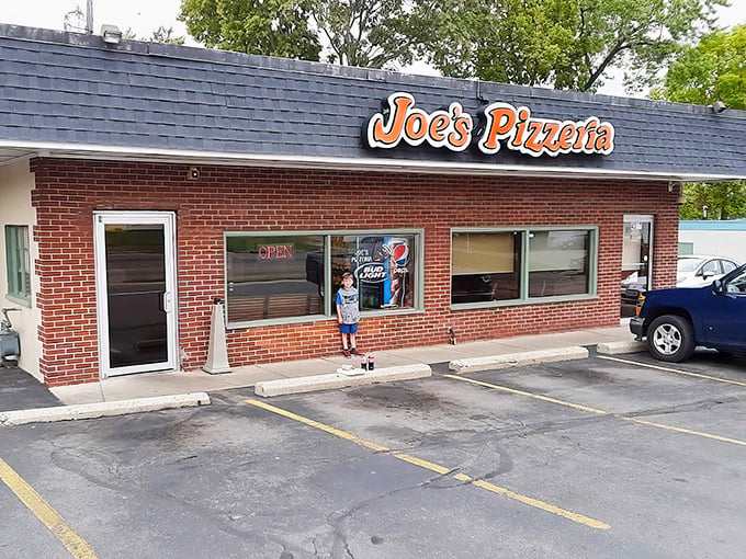 The storefront beckons like an old friend, promising that inside these brick walls awaits the comfort only perfect pizza can provide.