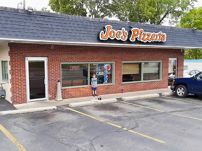 The storefront beckons like an old friend, promising that inside these brick walls awaits the comfort only perfect pizza can provide.