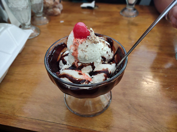 This isn't just a sundae&mdash;it's architecture in a glass, where hot fudge flows like lava around vanilla ice cream peaks, crowned with a cherry sentinel.