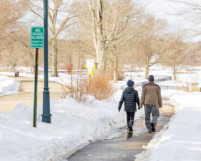 Swasey Parkway offers winter walkers a peaceful riverside path, where hand-holding couples create their own warmth against New Hampshire's chill.