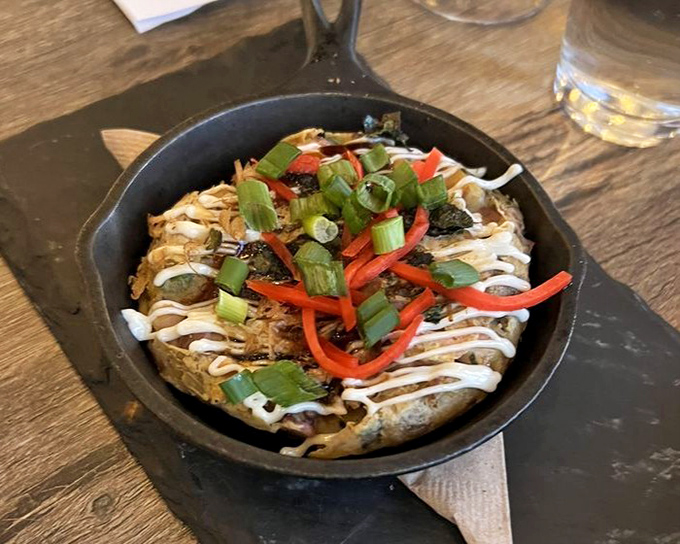 This Takoyaki arrives in its traditional cast iron vessel, topped with dancing bonito flakes and a drizzle of sauce that ties everything together.