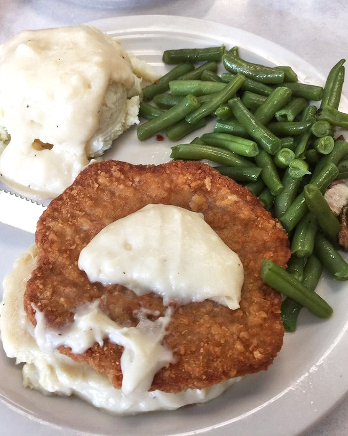 Chicken fried steak smothered in country gravy alongside mashed potatoes that could make a grown person weep. Green beans add color and the illusion of health.