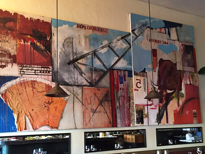 Bold, abstract artwork dominates the walls, creating a gallery-like atmosphere that feeds your eyes while the kitchen feeds your stomach.