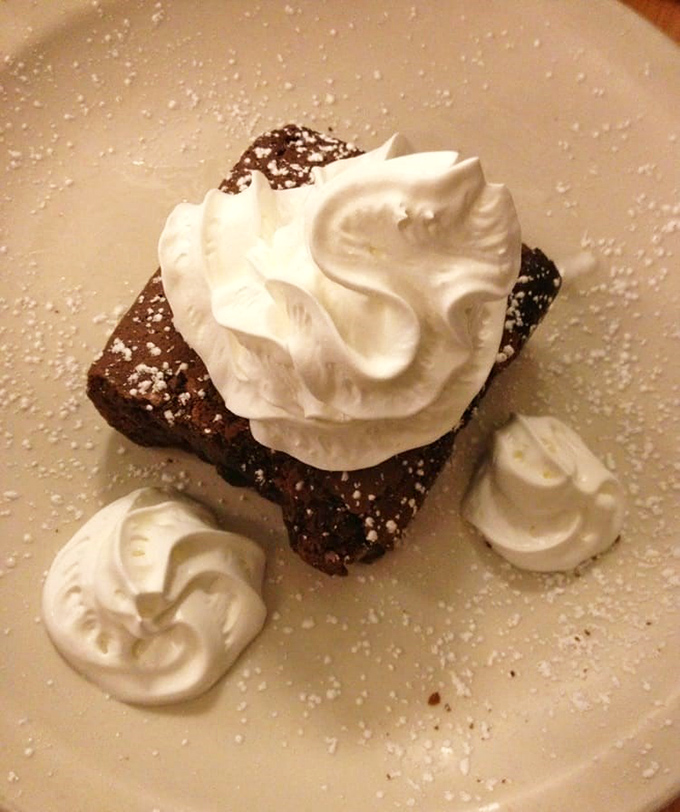 This brownie isn't just warm &ndash; it's having a full-on romance with that cloud of whipped cream. Powdered sugar plays matchmaker.