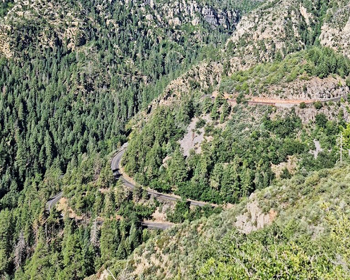 The serpentine road below traces the canyon's contours like a gentle caress, each curve revealing new perspectives for drivers with the patience to slow down.