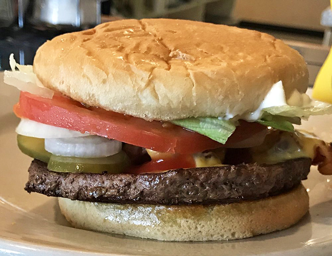 A burger built with architectural precision—each layer visible like geological strata of deliciousness waiting to be excavated.
