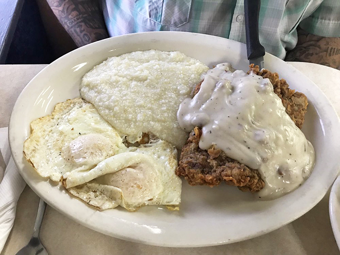 Country-fried steak smothered in gravy alongside eggs and grits. This plate has more Southern charm than a porch full of rocking chairs.