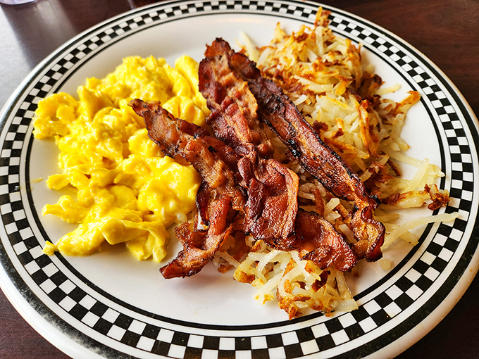 The breakfast trinity: golden eggs, perfectly crisped bacon, and hash browns with the ideal balance of crunch and tenderness. Morning salvation on a plate.