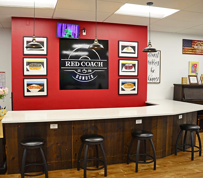The striking red accent wall and carefully arranged donut portraits create an altar to fried dough that feels both reverent and playful.