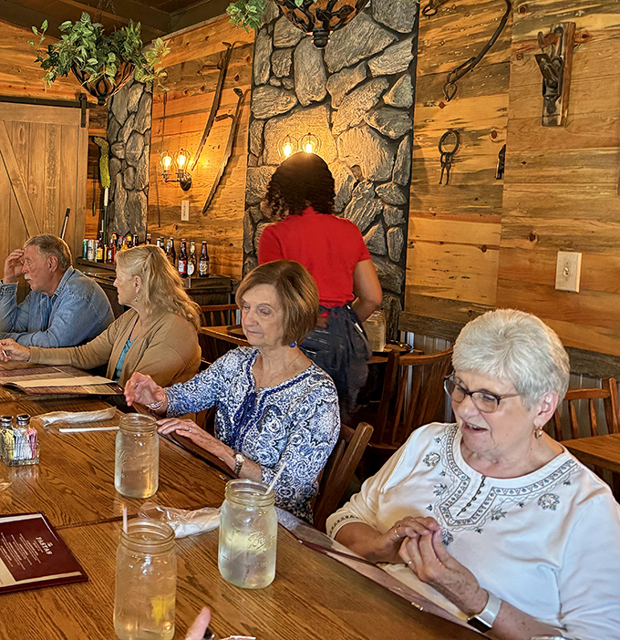 Diners enjoying the warm wooden interior with stone accents&mdash;where conversations flow as freely as the sweet tea refills.