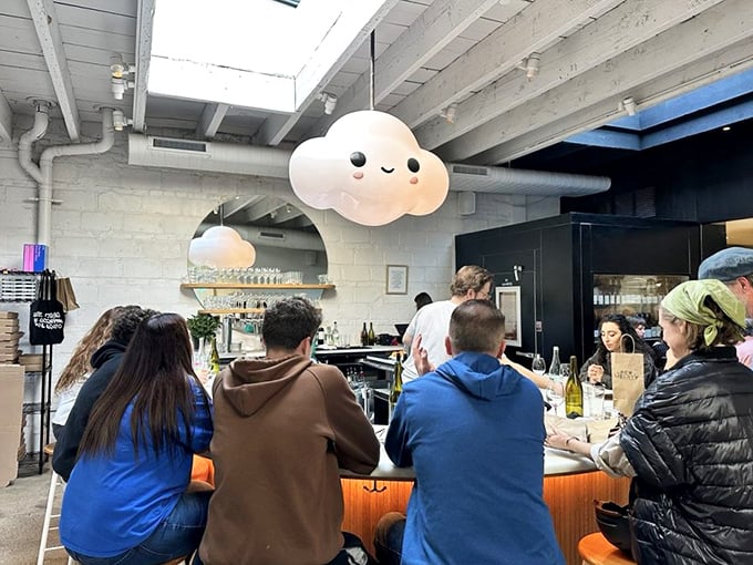 Happy diners gathered at the bar under that smiling cloud lamp&mdash;a community united by the universal language of exceptional pizza.