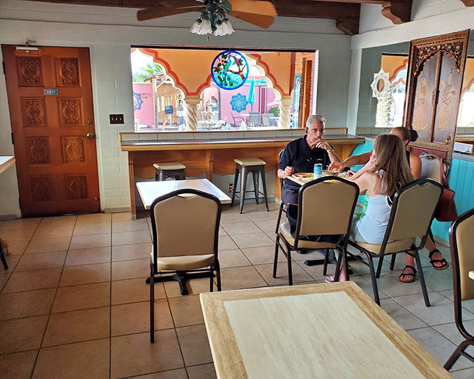 The stained glass window casts colorful light across simple tables, creating an atmosphere where conversations flow as easily as the vegetarian gravy.