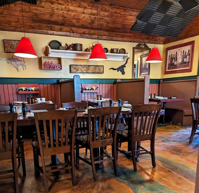 Red pendant lights hang from wooden ceilings like culinary exclamation points, illuminating a dining room where comfort meets classic steakhouse charm.
