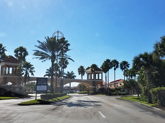Another view of the iconic entrance arch, framed by palm trees against a perfect Florida sky &ndash; retail therapy with a vacation vibe.