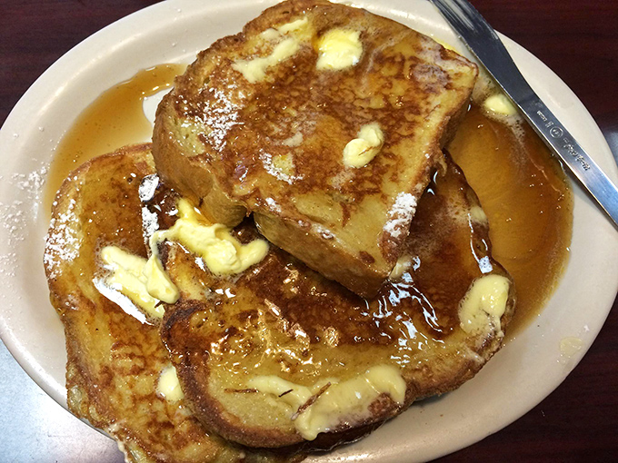 French toast that's essentially dessert masquerading as breakfast, swimming in syrup and melting butter like it's auditioning for a food commercial.