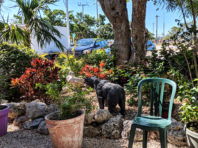 Garden seating surrounded by tropical plants and a black bear statue &ndash; because Florida never got the memo about conventional restaurant d&eacute;cor.