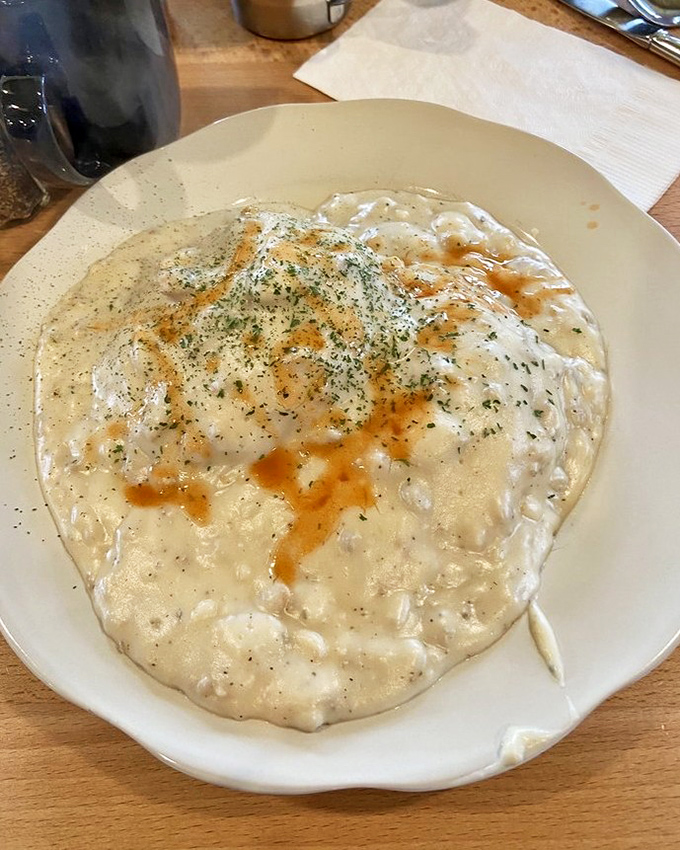 Sausage gravy cascading over biscuits like a delicious avalanche of Southern comfort food excellence.