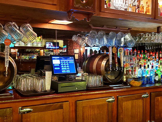 Behind the bar, where magic happens &ndash; glasses hanging like crystal stalactites above a wooden landscape of bottles and taps.
