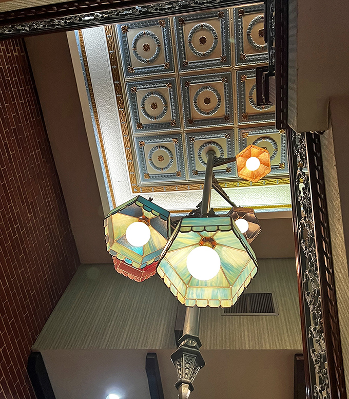 The ornate tin ceiling and colorful pendant lights create an atmosphere that whispers, "Your Instagram feed can wait&mdash;dinner is served."