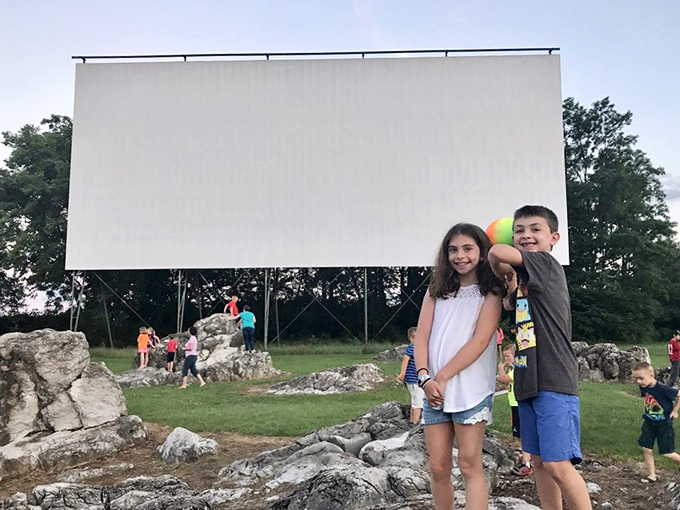The limestone rocks near the screen create a natural playground where kids burn energy before settling in for the feature presentation.