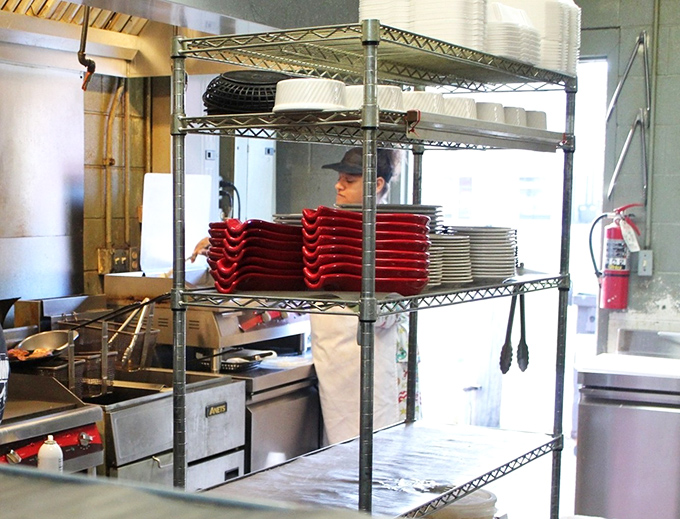 A glimpse into the kitchen battlefield where breakfast heroes work their magic, red plates stacked like medals of honor waiting to be awarded.