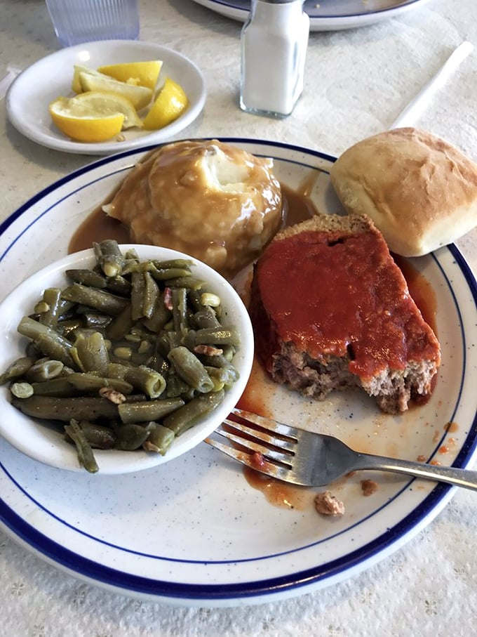 Meatloaf, green beans, and mashed potatoes swimming in gravy - the kind of plate that makes you want to hug the cook.